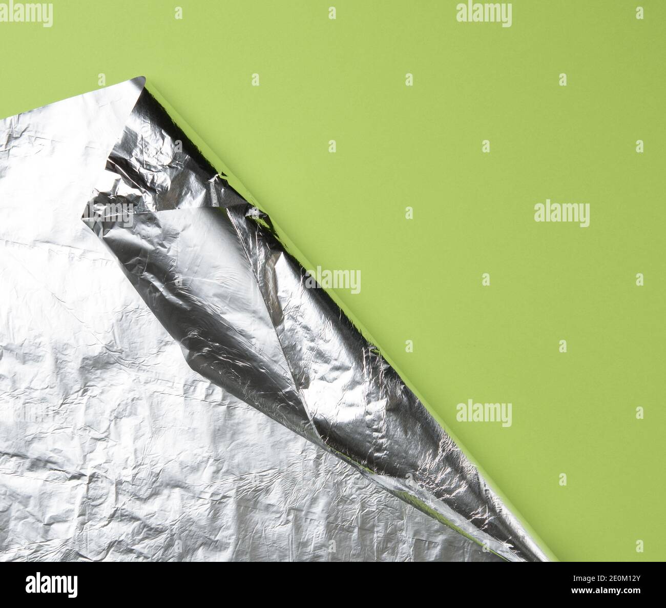 rolled sheet of foil on a green background, the corner is folded, copy ...