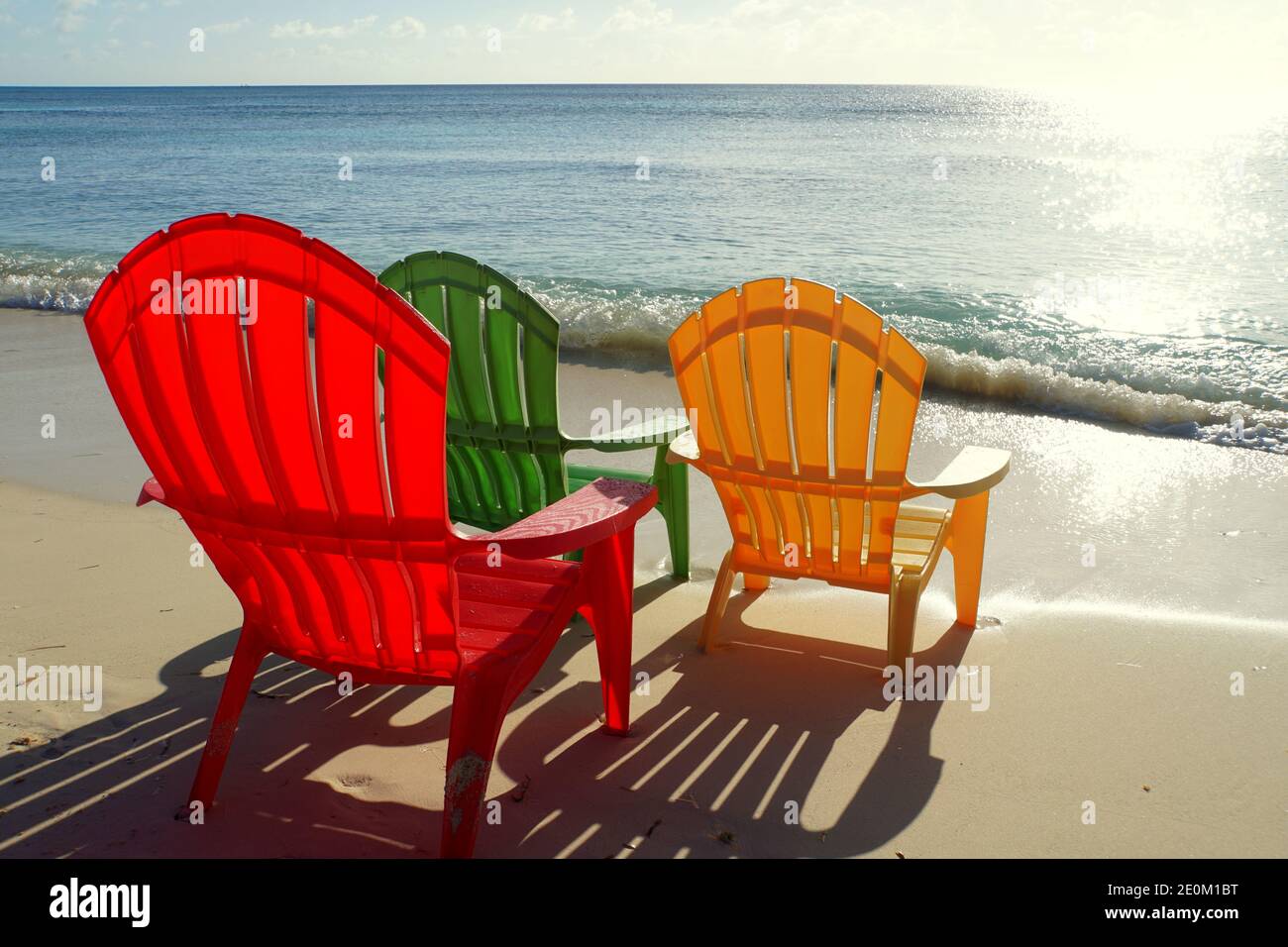 Colorful chairs facing the bright sun and overlooking beautiful blue ...