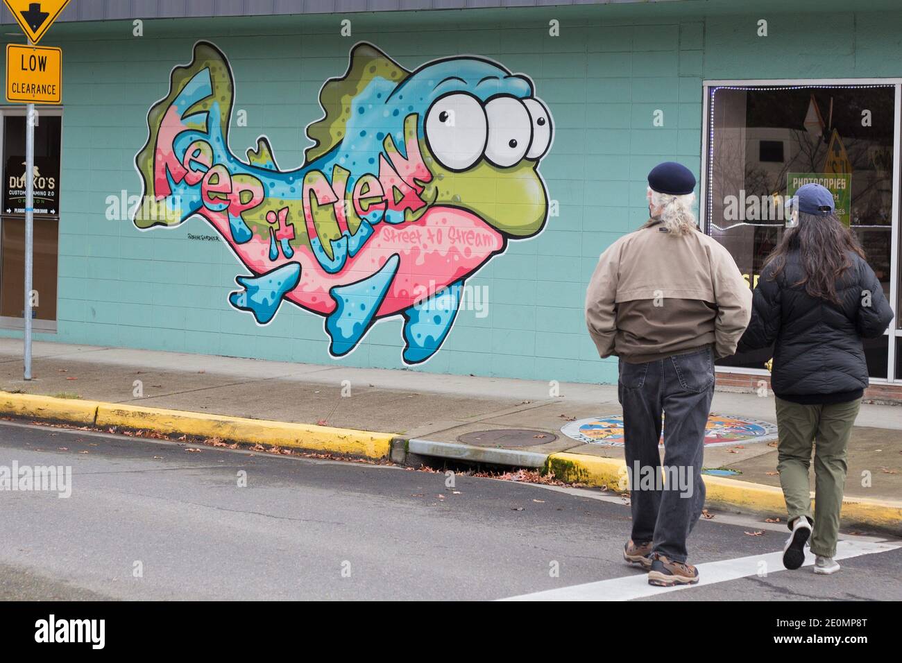 A couple looking at a Simpsons style mural of a three-eyed fish, in ...