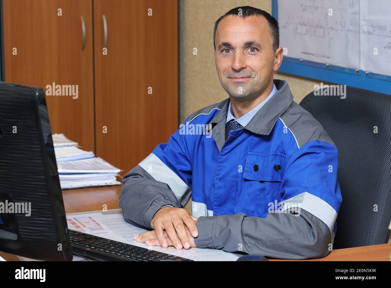 Happy engineer sitting at his Desk in a chair. Portrait of a production ...