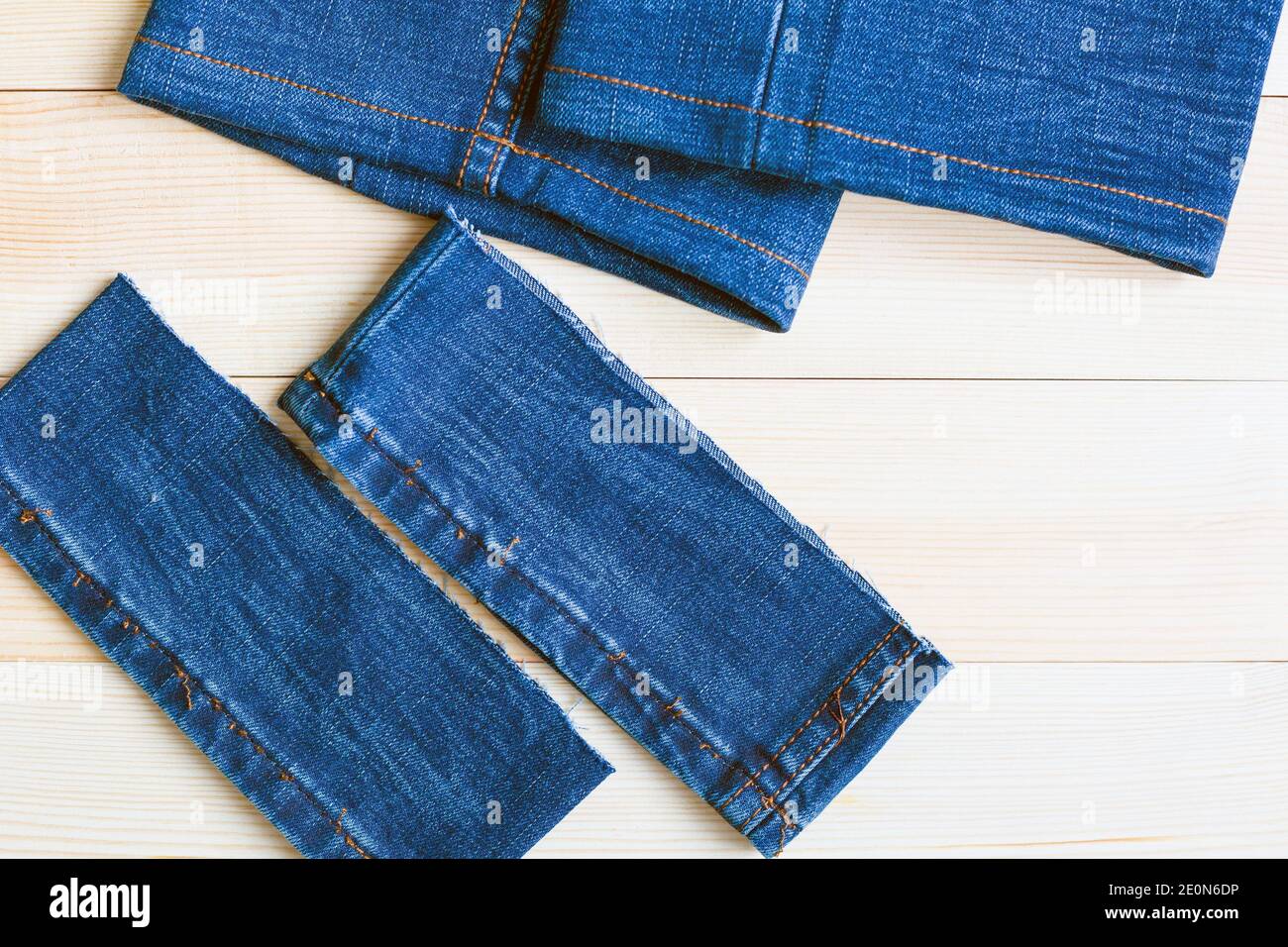 Cut pieces of long denim pants on a wooden background Stock Photo - Alamy
