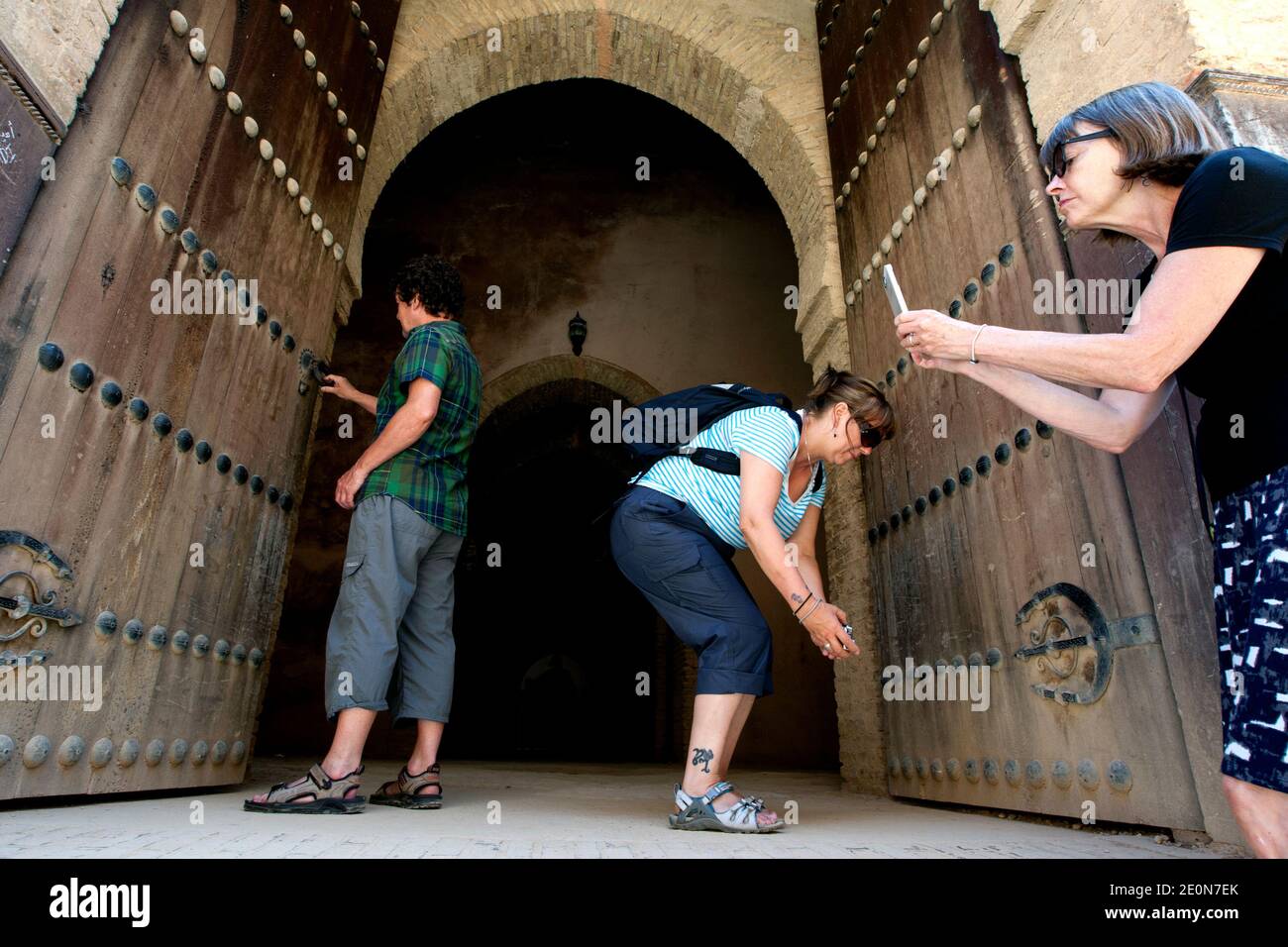 A group of tourists photographing the wooden doors to the old granaries of the Heri es-Souni at ...