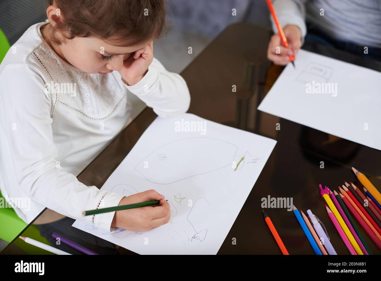 Top view of a baby girl in white shirt drawing with color pencil Stock ...