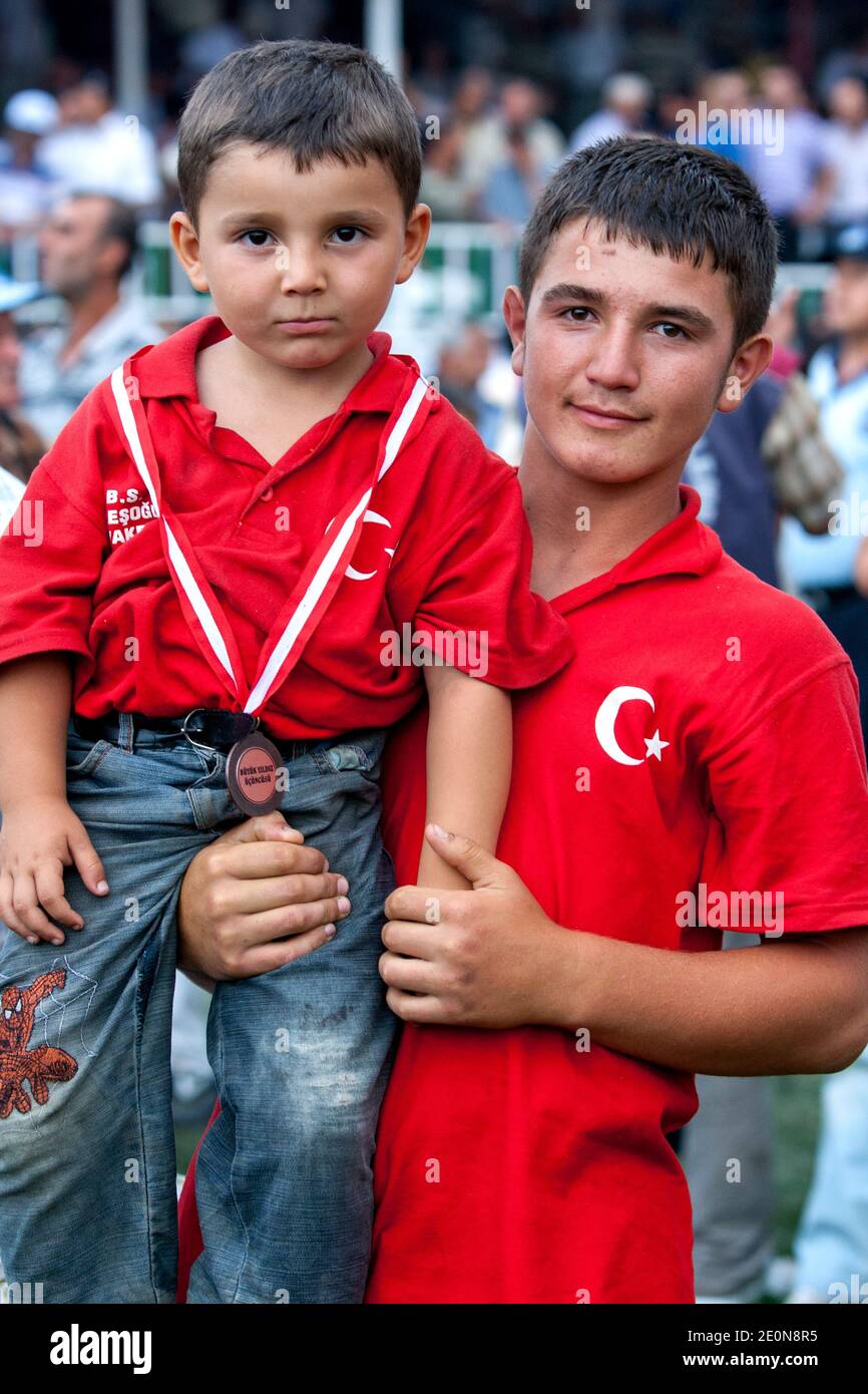 A Turkish boy holds his younger brother who is wearing his medal at the ...