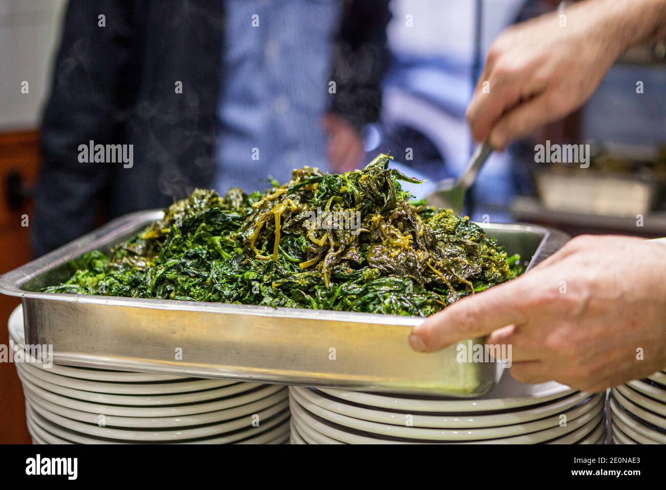 Sauteed sprouting broccoli being served from a steel tray, resting on ...
