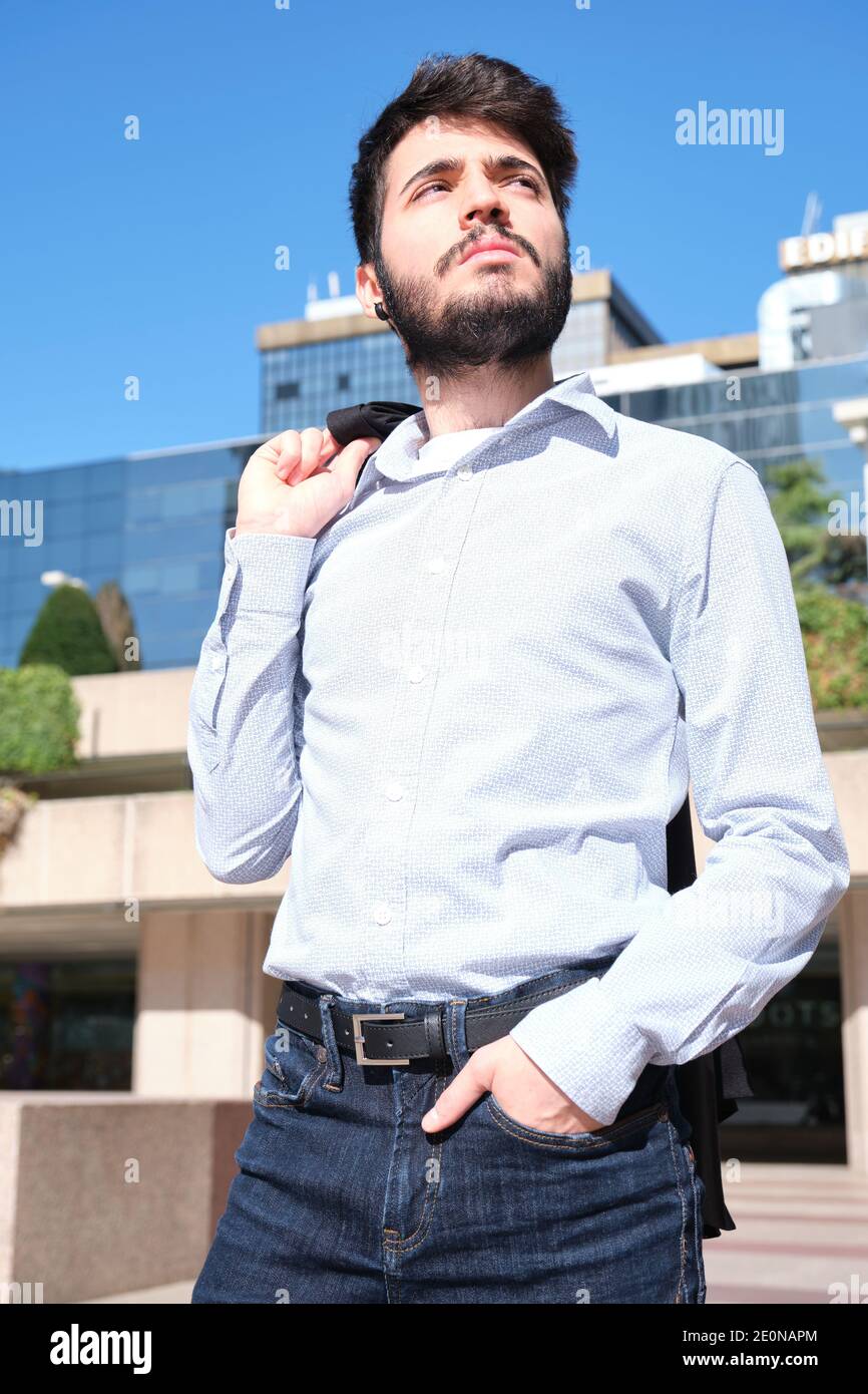Young business man portrait looking up with buildings in the background ...