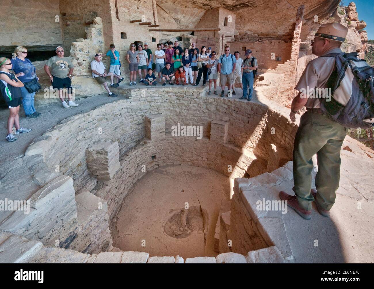 Park guide and visitors over kiva (ceremonial chamber) at Balcony House ...