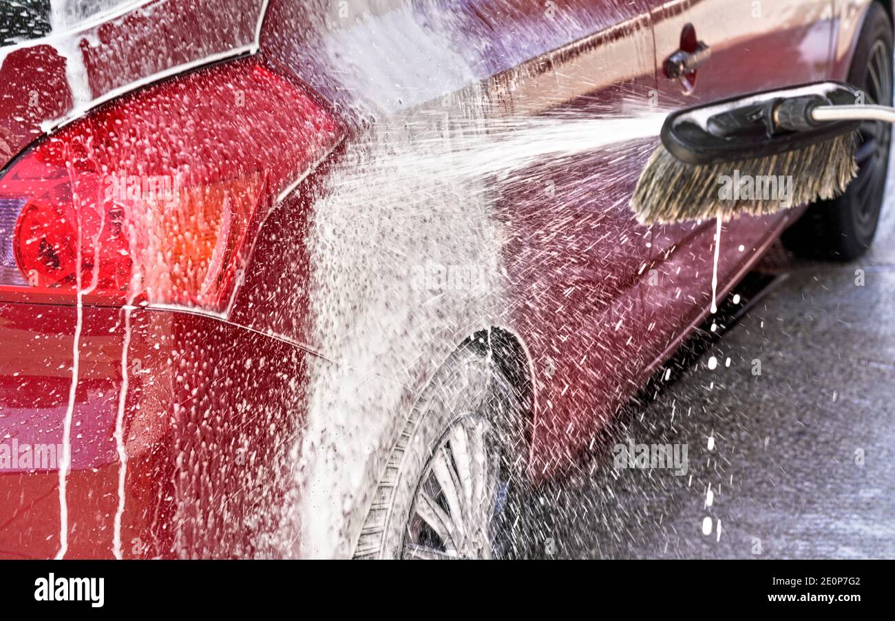 Red car washed in self serve carwash, detail on white soap foam ...