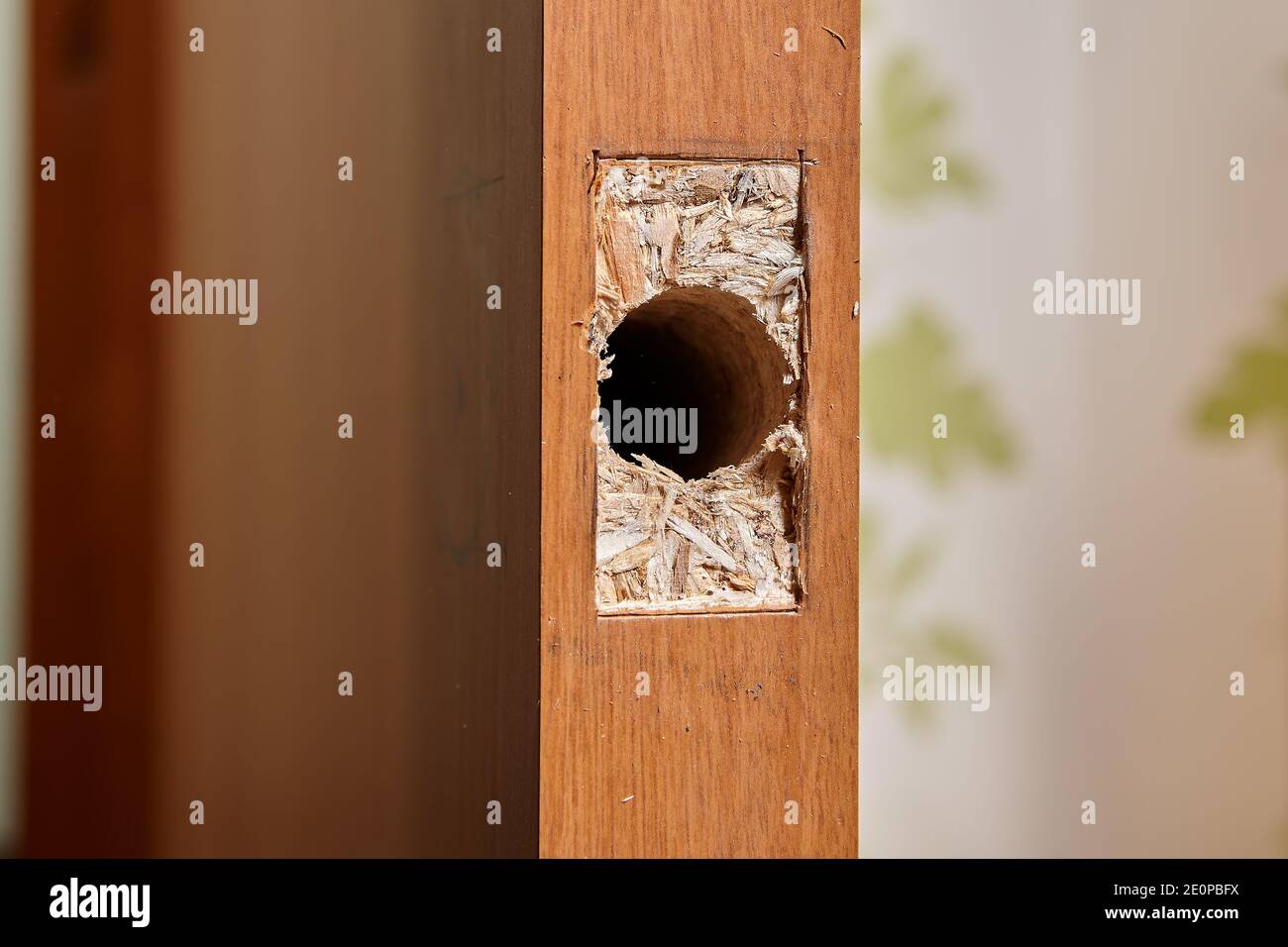 The carpenter drilled a hole for the latch of the door lock in the ...