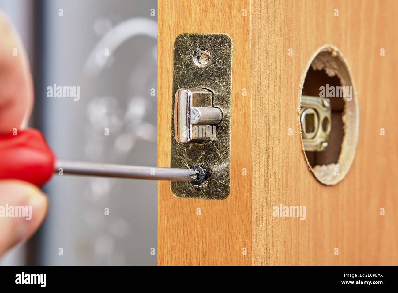 Locksmith secures the latch into the wood interior door with 2 screws ...