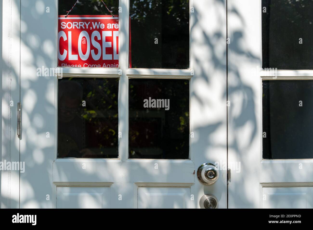 Red closed sign hanging on the white entrance door of a business office ...