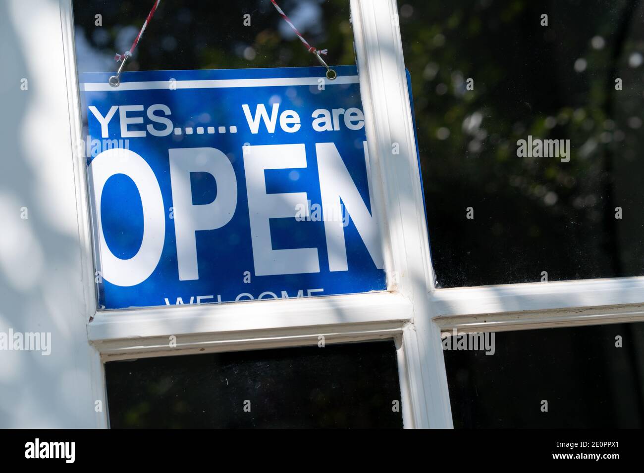 Blue open sign hanging on the white entrance door of a business office ...