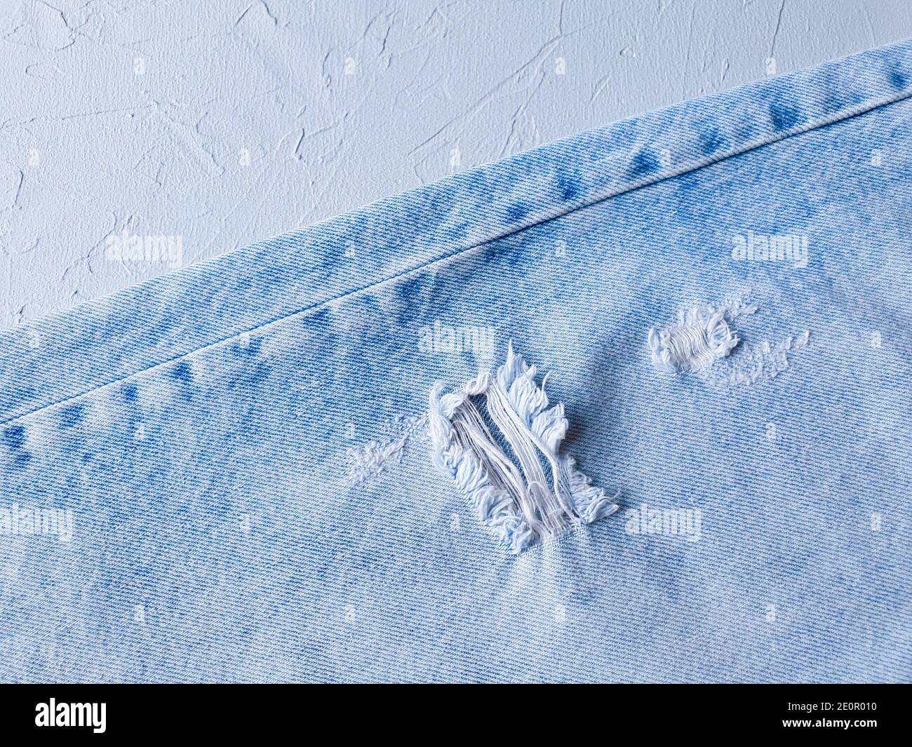 Blue holey jeans on a concrete gray background. Denim. Hole on the ...