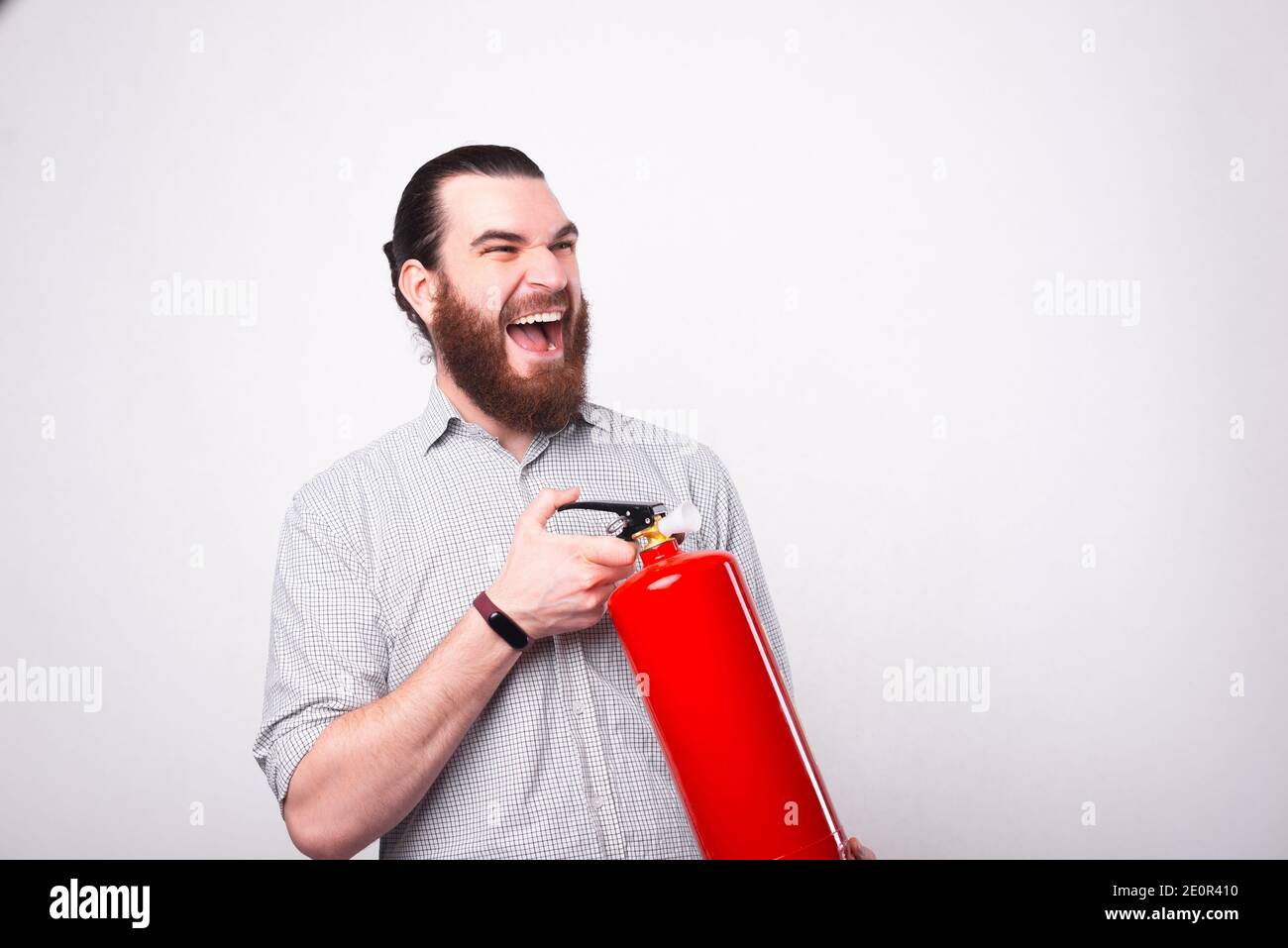 A bearded young man screaming is holding a fire extinguisher near a ...