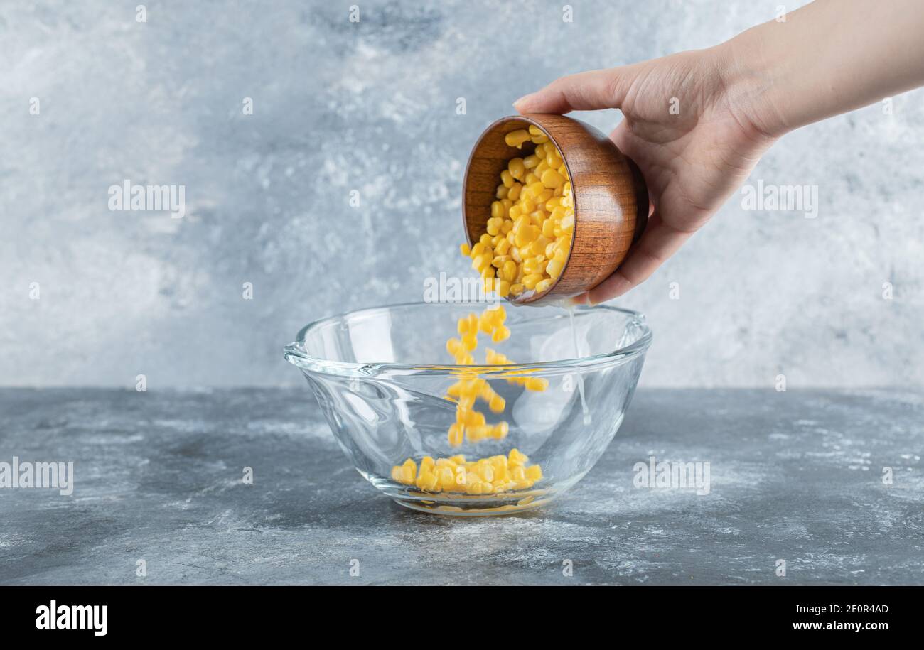 Female hand adding sweet corns into glass bowl Stock Photo - Alamy