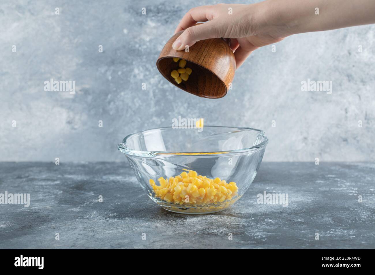 Female hand adding sweet corns into glass bowl Stock Photo - Alamy
