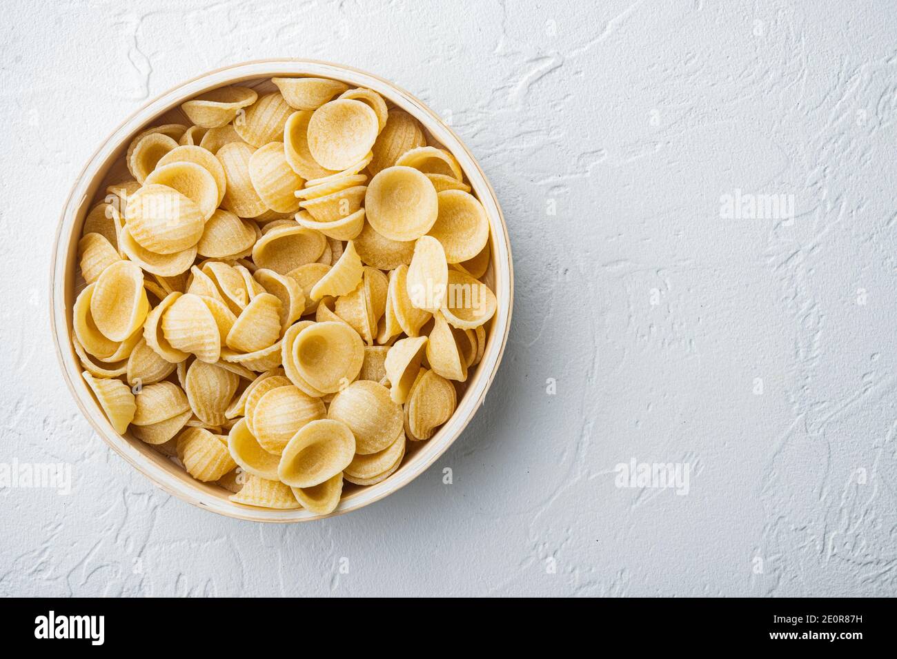 Dried pasta shells in bowl, on white background, flat lay with copy ...