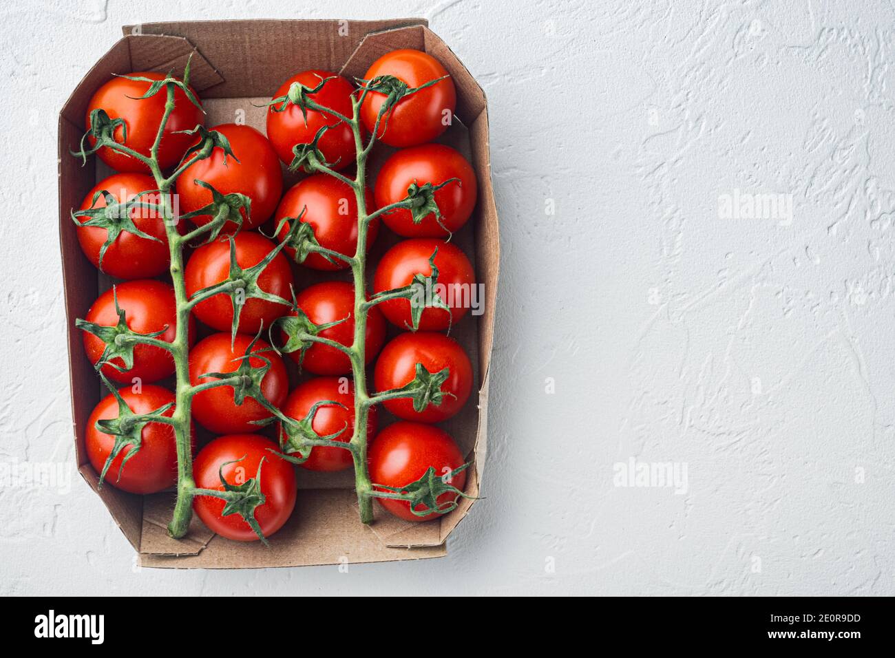 Ripe cherry tomatoes in box, on white background, top view with copy ...