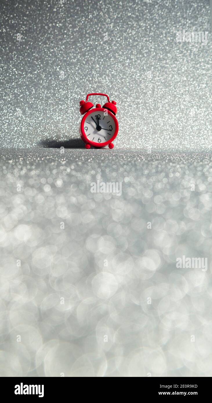 The red clock shows five minutes to twelve on a silver glitter ...