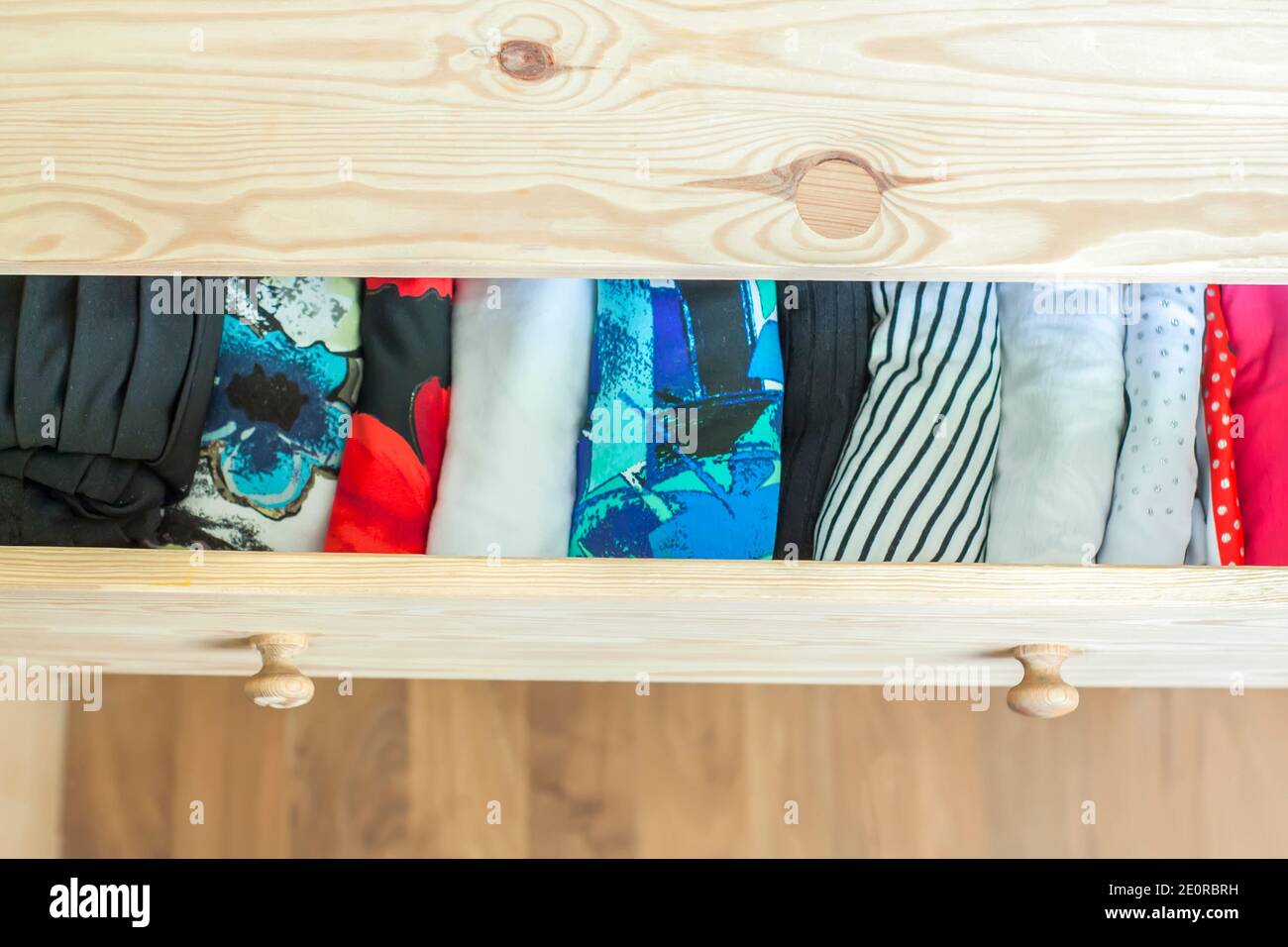 Open light wooden dresser drawer with colorful clothes Stock Photo - Alamy