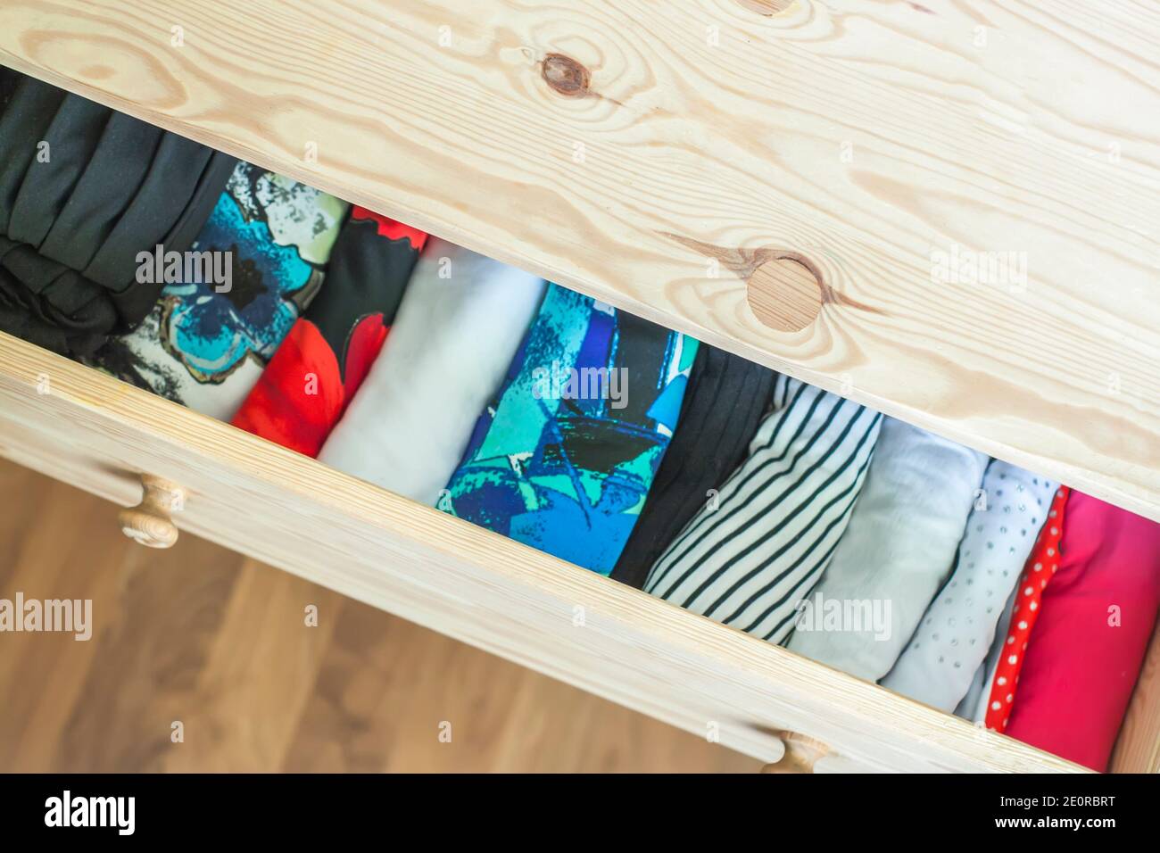 Open light wooden dresser drawer with colorful clothes Stock Photo - Alamy