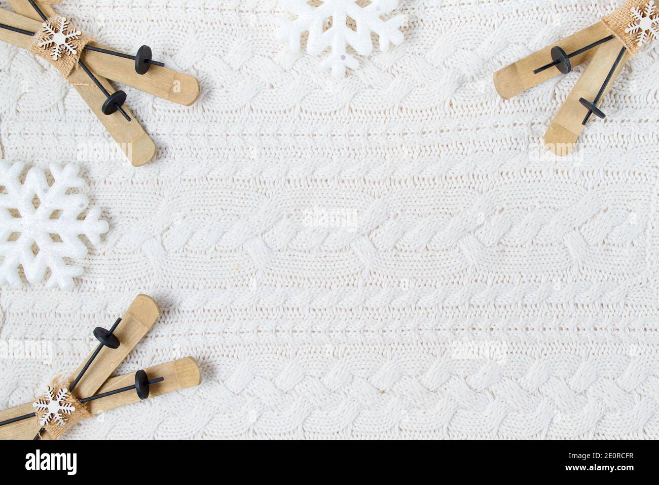 winter flat lay with skis and snowflakes on white knitted background ...