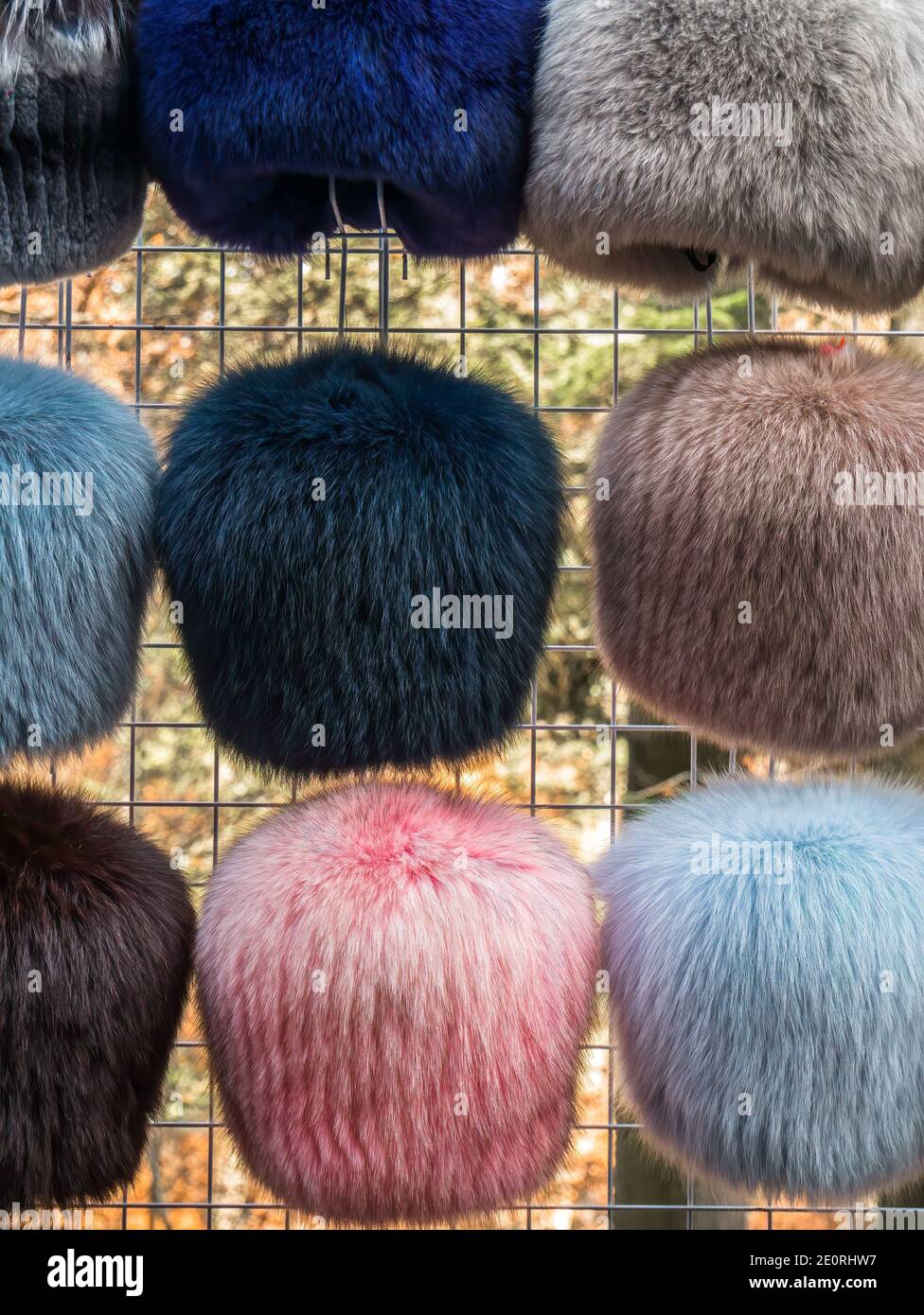 Colored (synthetic) woman's fur hats on display outdoor on a fence ...