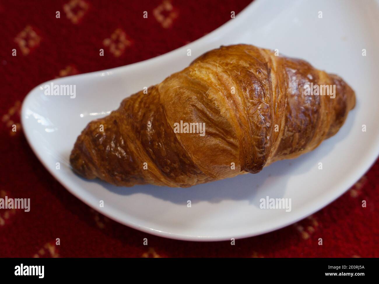 Single croissant on crescent shaped white dish with copy space Stock ...