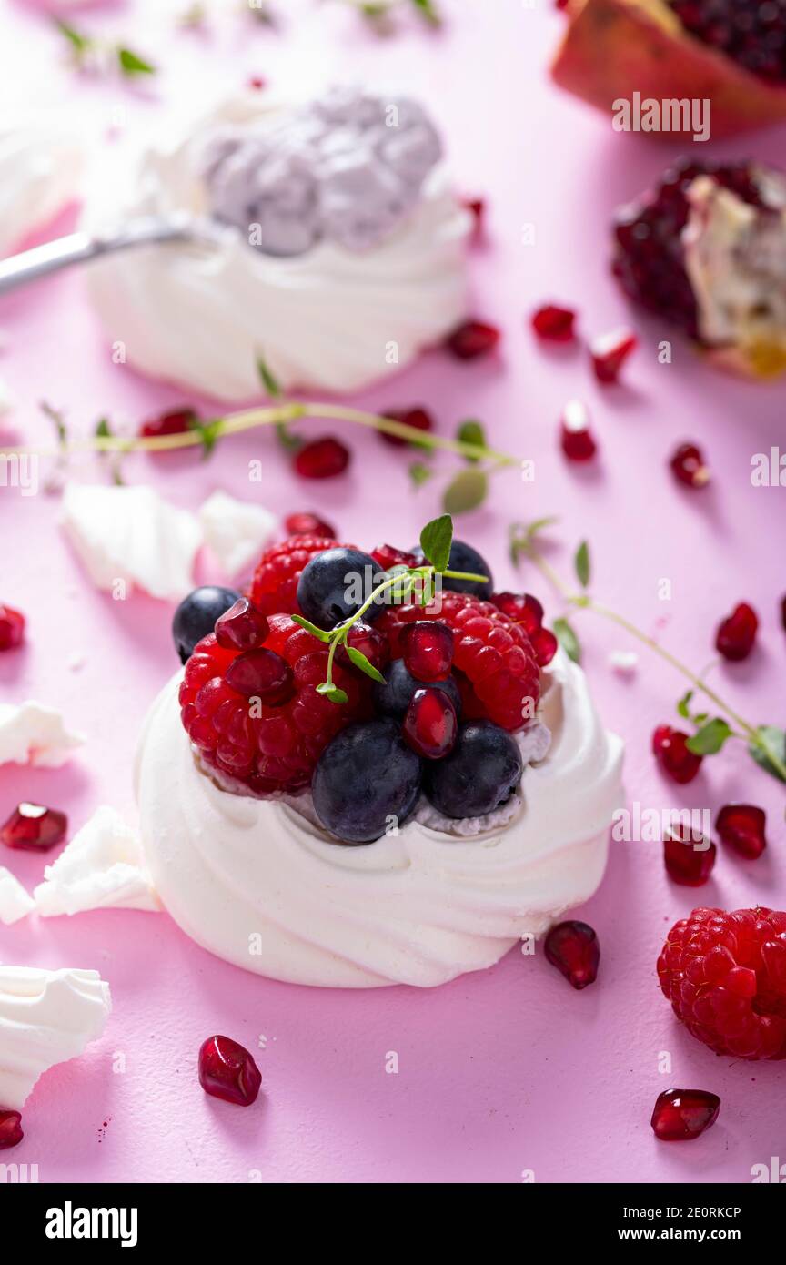 Pavlova meringue cake with berries on dusted sugar pink background ...
