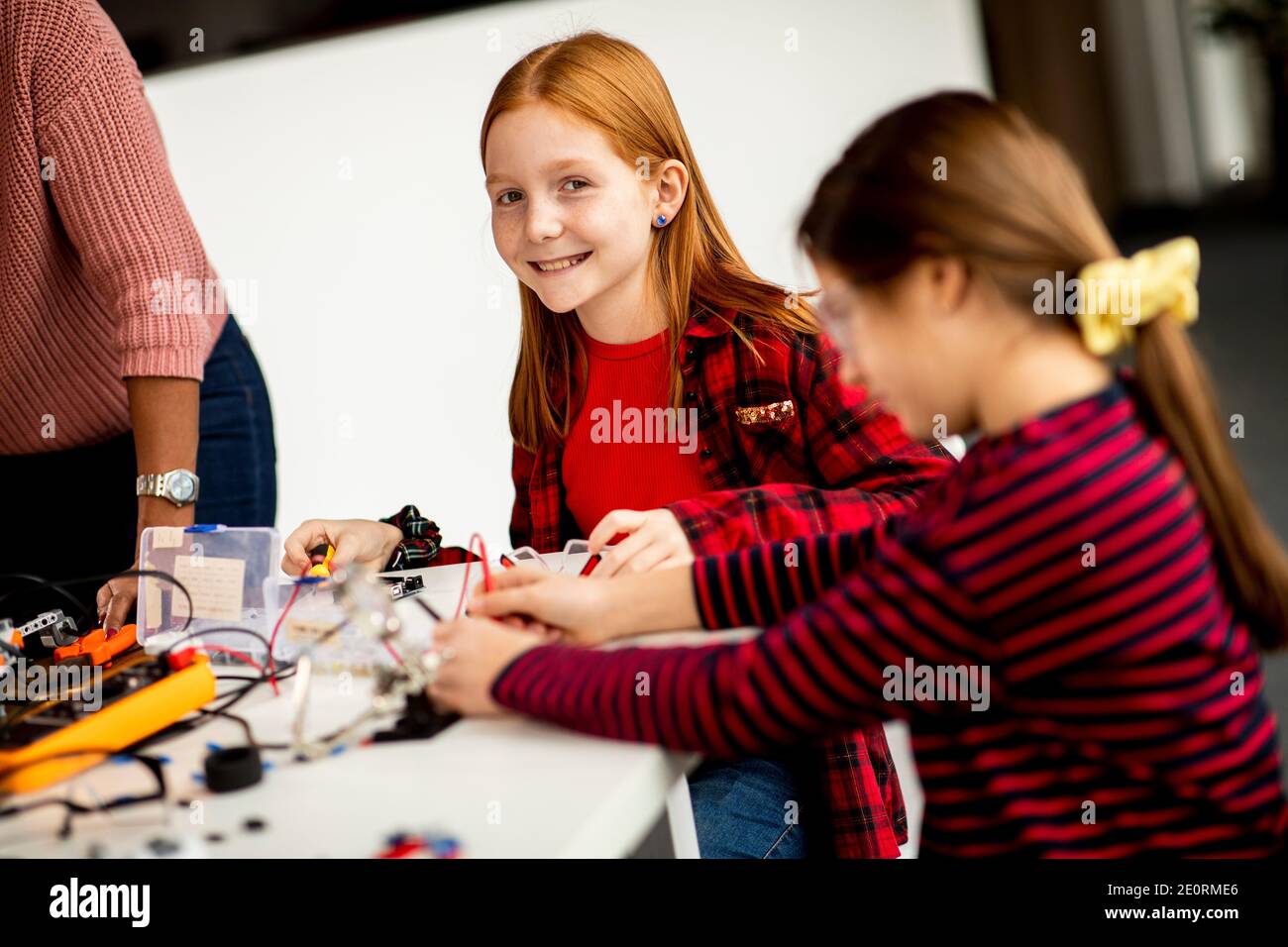 Group of cute little girls programming electric toys and robots at ...