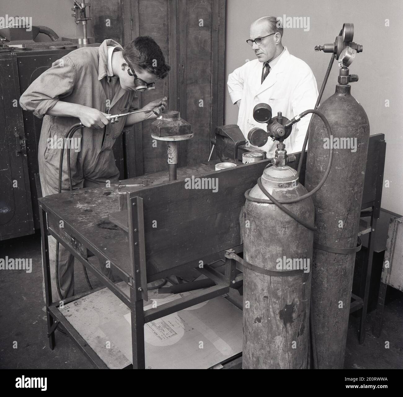 1950s, historical, Under the watchful eye of a white-coated tutor, a ...