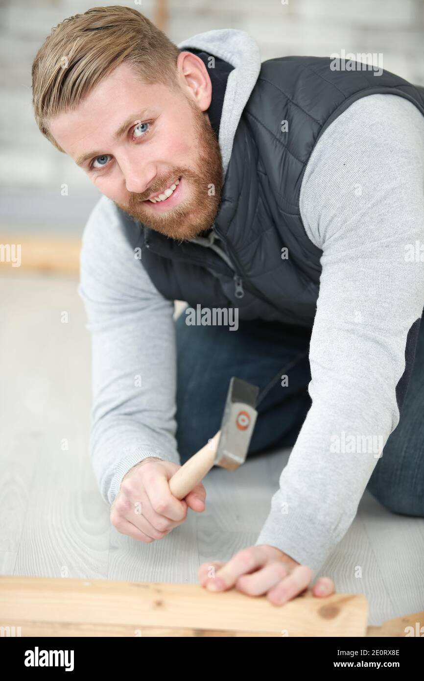 handsome guy hammering nail into wood plank Stock Photo - Alamy