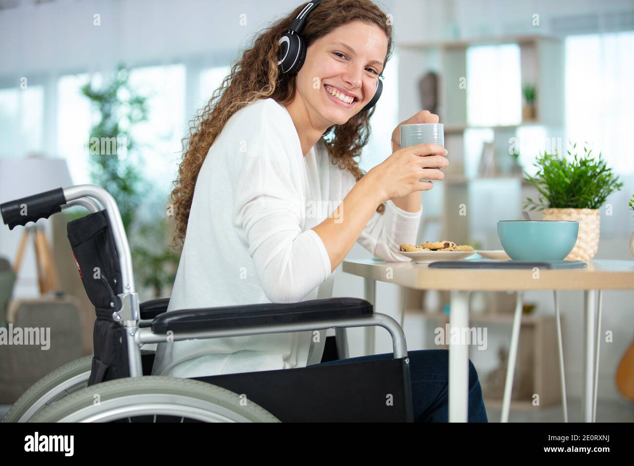 young woman in wheelchair eating breakfast and wearing headphones Stock ...