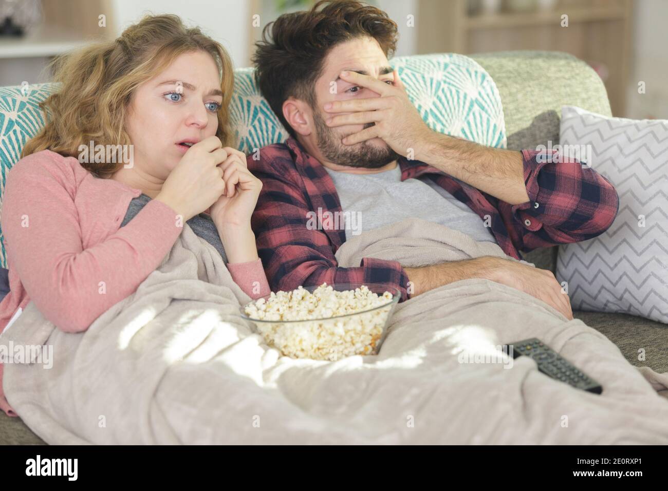 funny couple sitting on sofa watching horror movie Stock Photo - Alamy