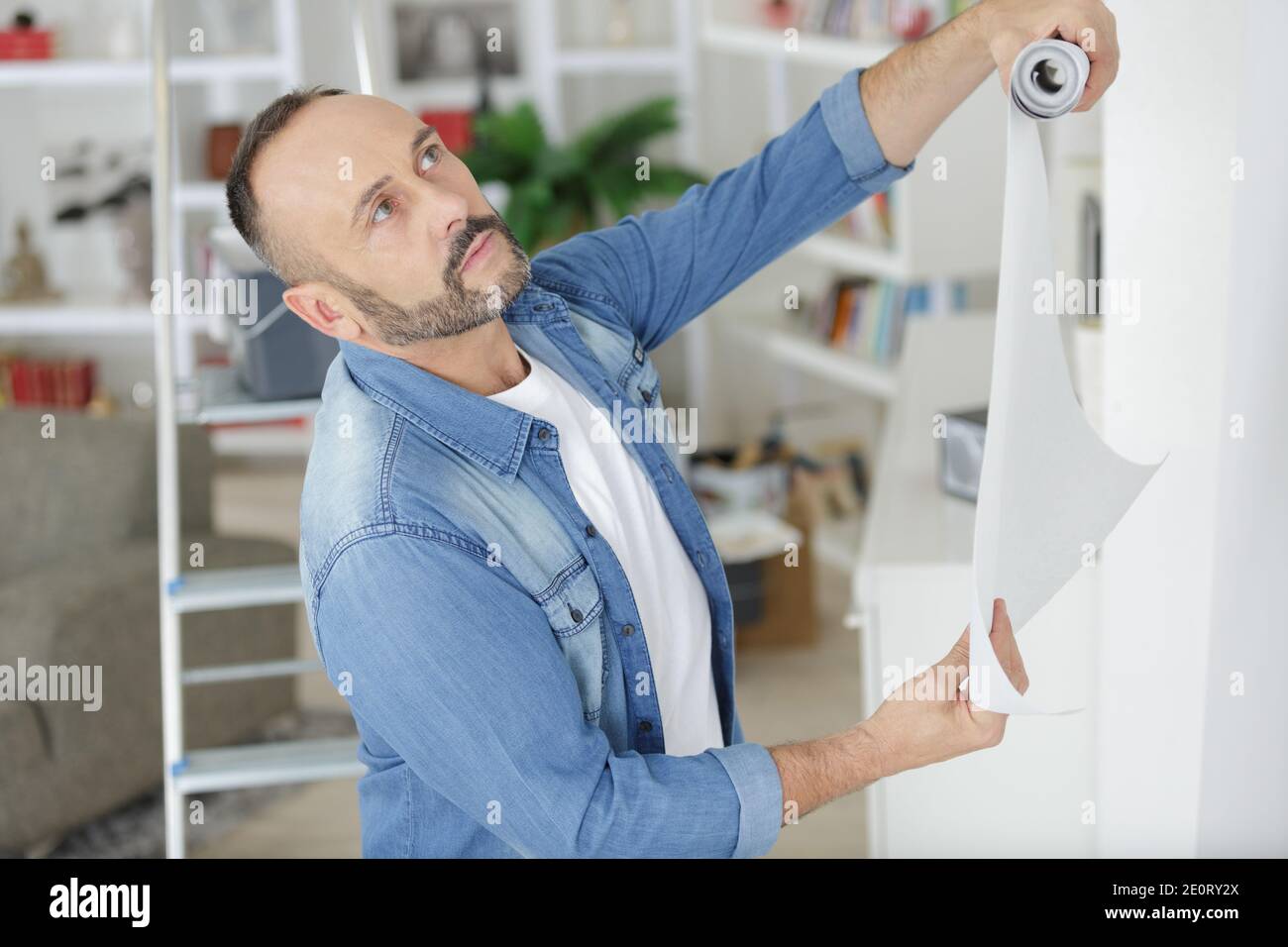 a man is smoothing wallpaper Stock Photo - Alamy