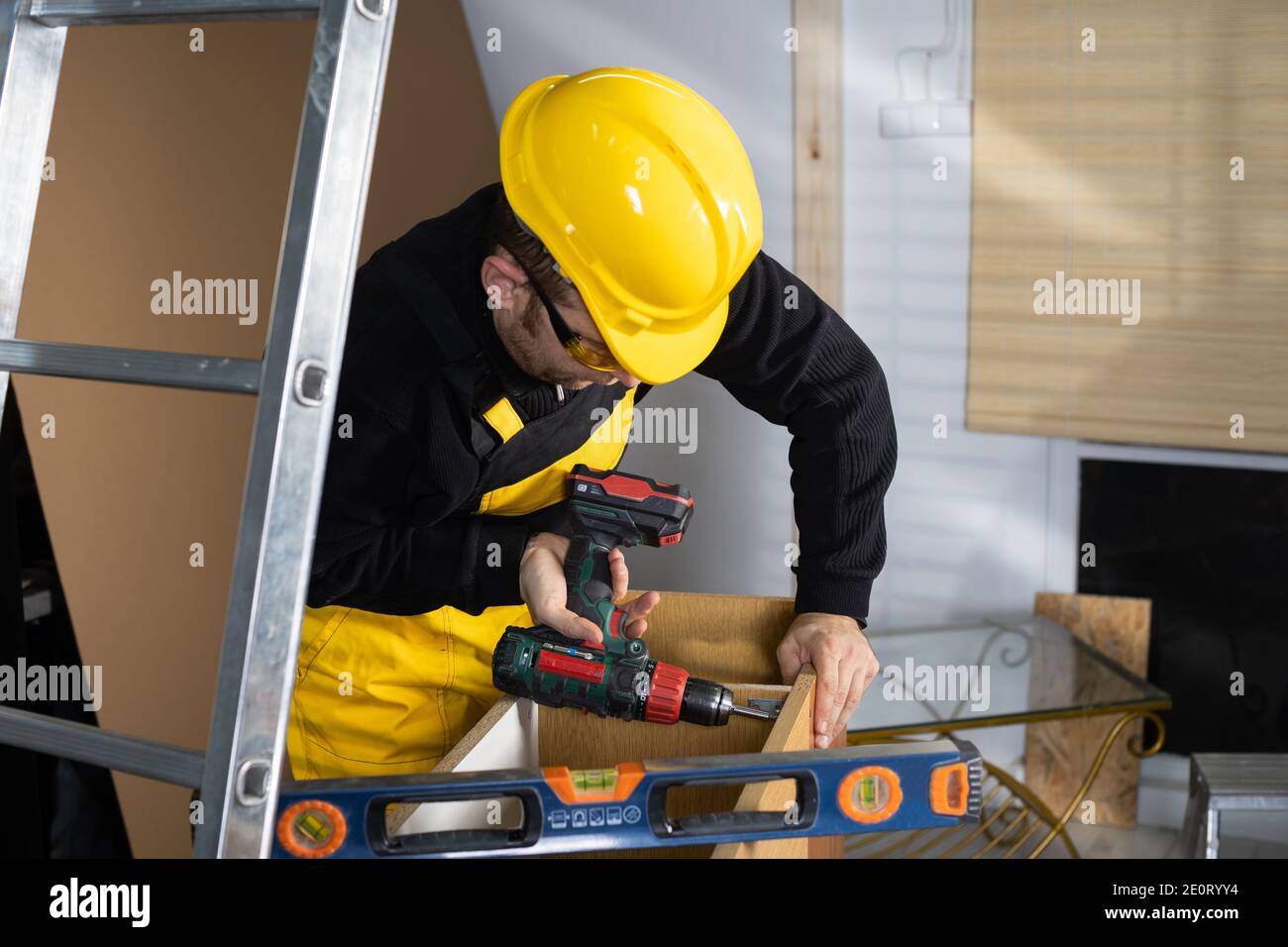 A construction worker uses a screwdriver to screw a cabinet made of a ...
