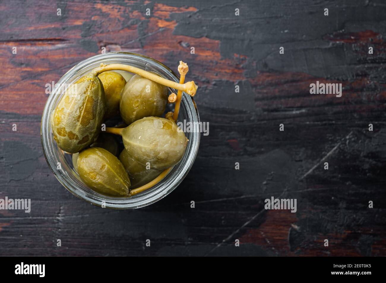 Capers, marinated in oil, on old wooden table, top view with copy space ...