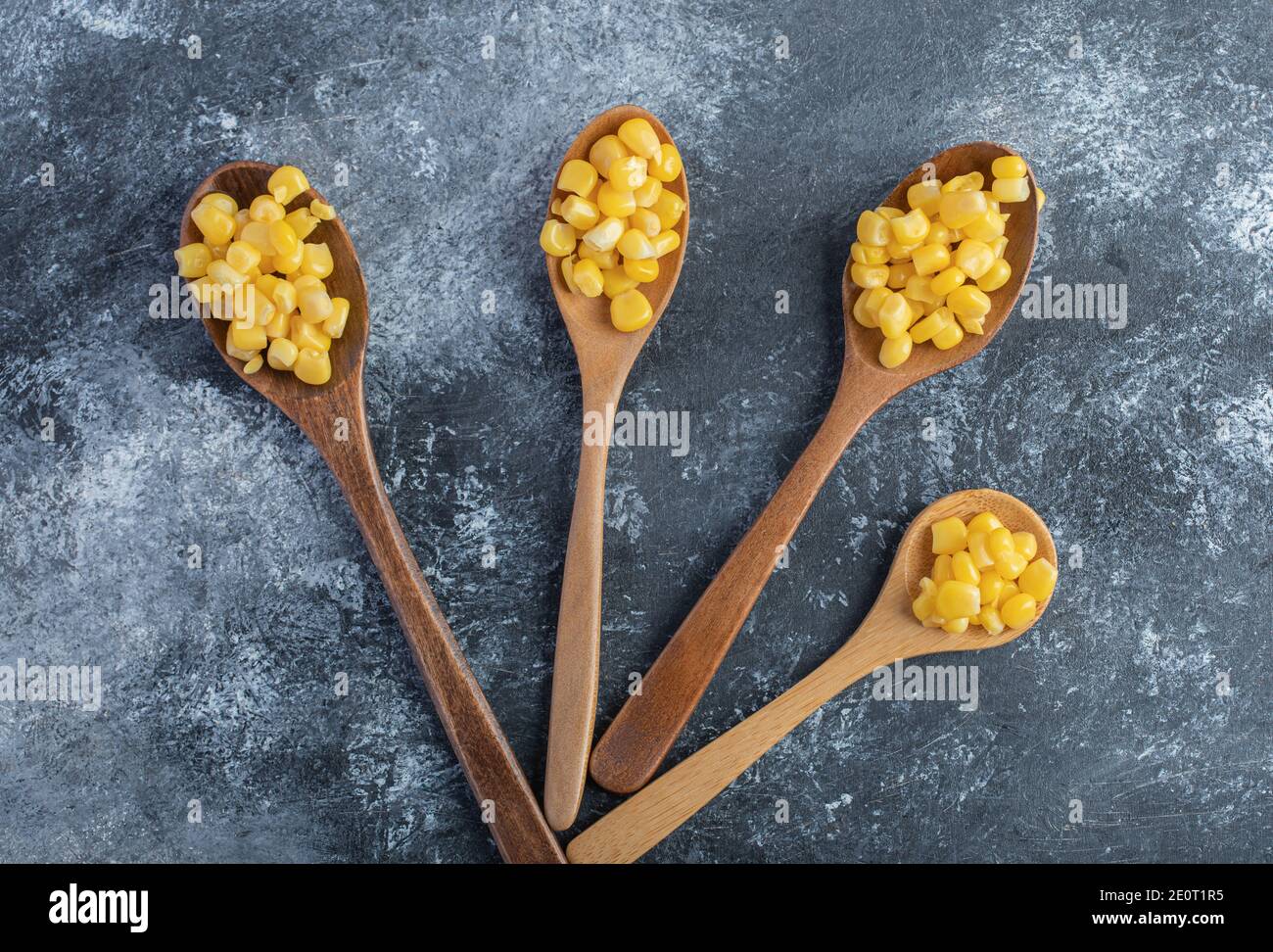 Wooden spoons of sweet corns on marble background Stock Photo - Alamy