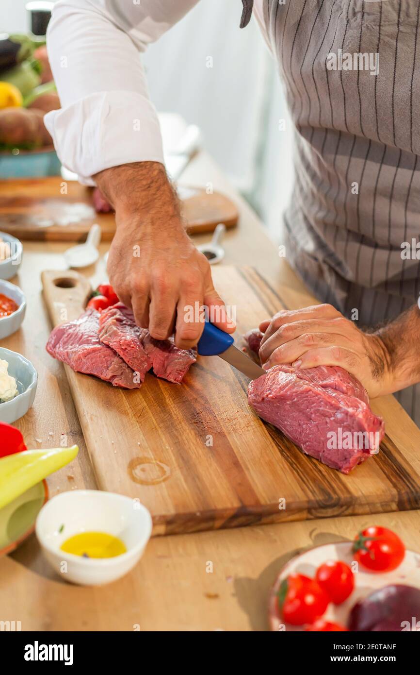 A close-up of the chef's hands cutting meat into thin pieces with a ...