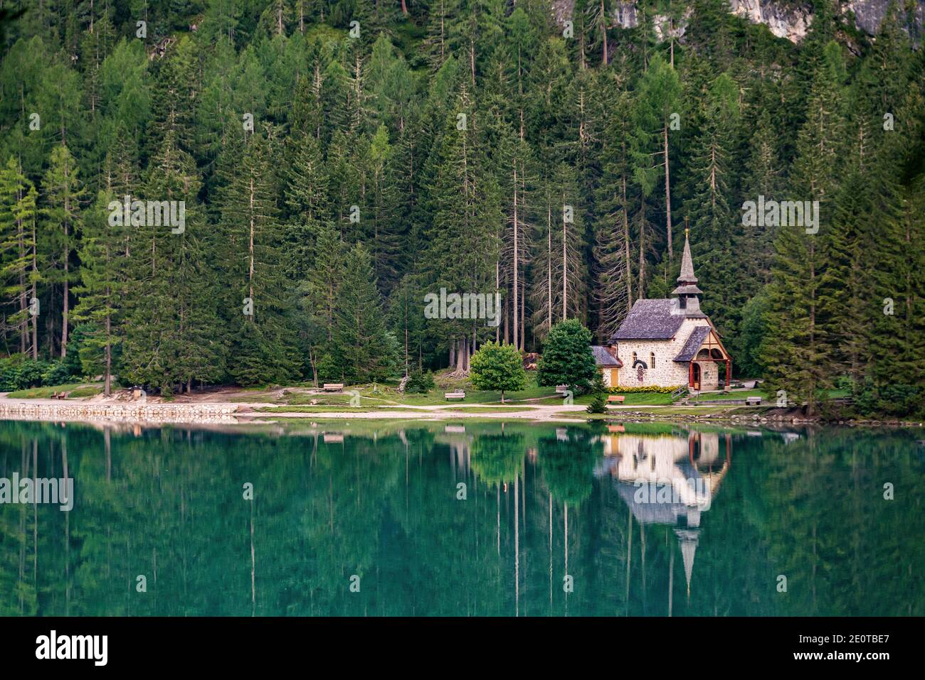 Chapel and trees are reflected in the water of Lake Braies in the ...