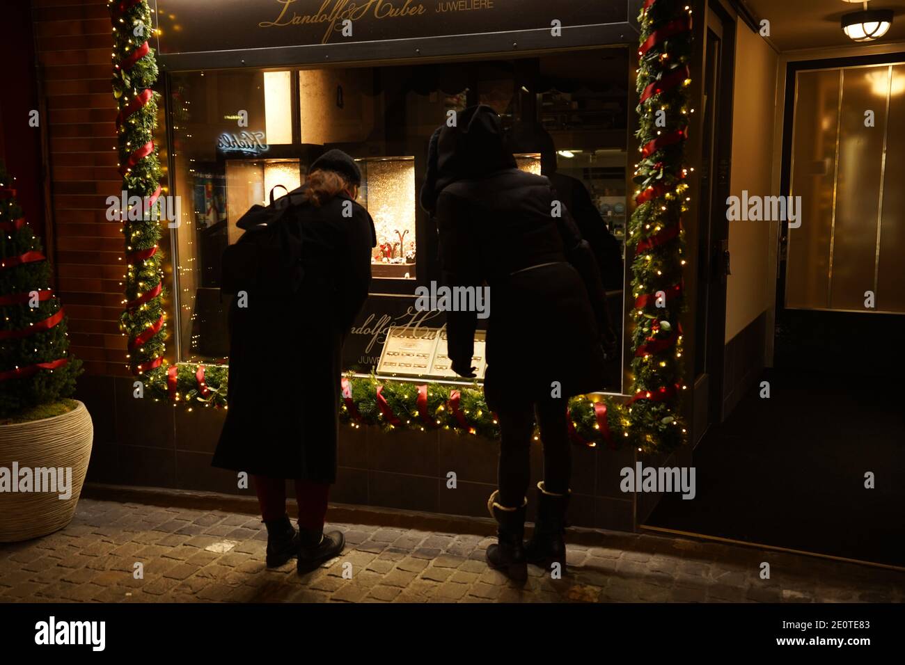 Two female pedestrians standing in front of a store window in dark ...