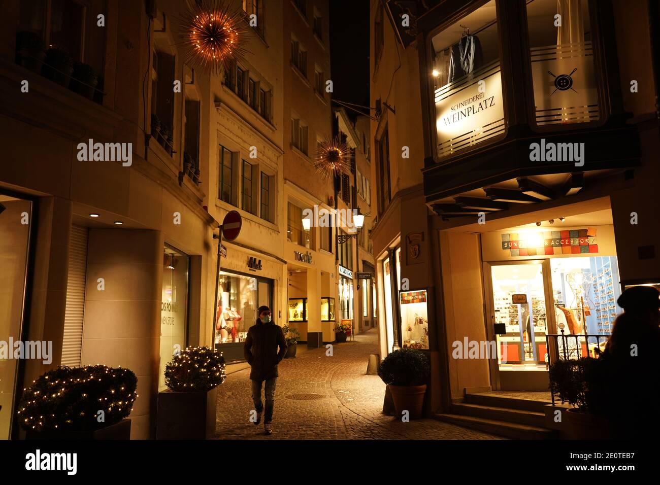 Pedestrians walking in front of a luxury store window in dark evening ...