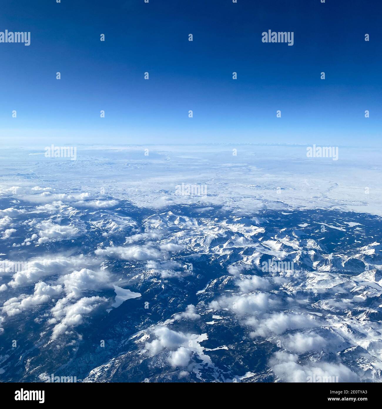 An aerial view from an airplane window of mountains, snow, clouds and ...