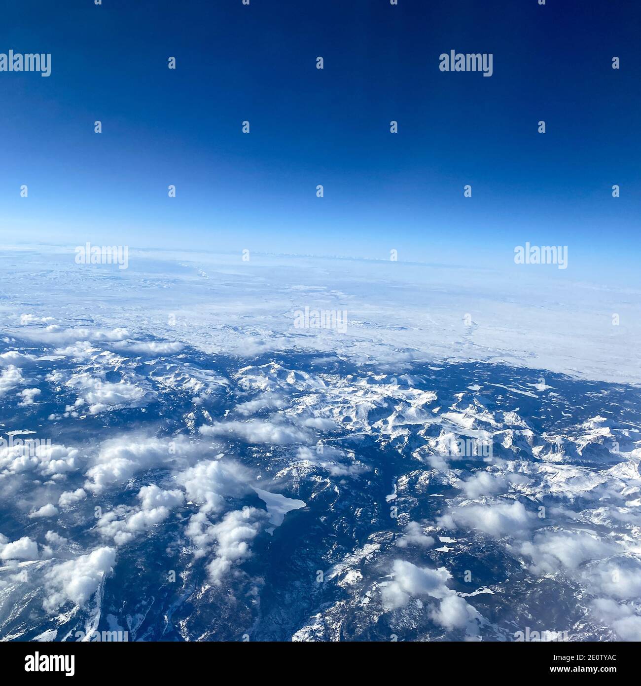 An aerial view from an airplane window of mountains, snow, clouds and ...