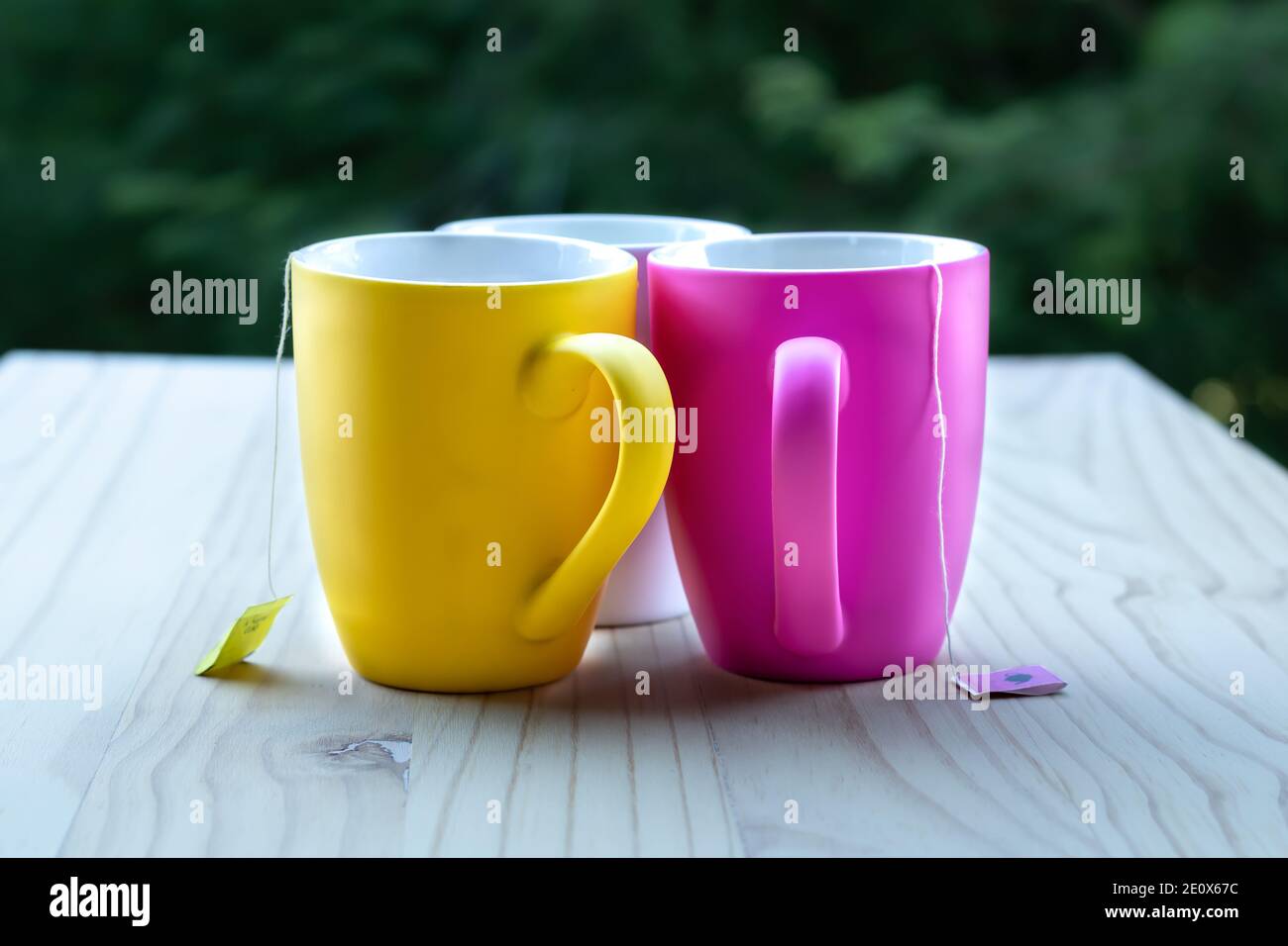 Three multi coloured mugs with tea Stock Photo - Alamy