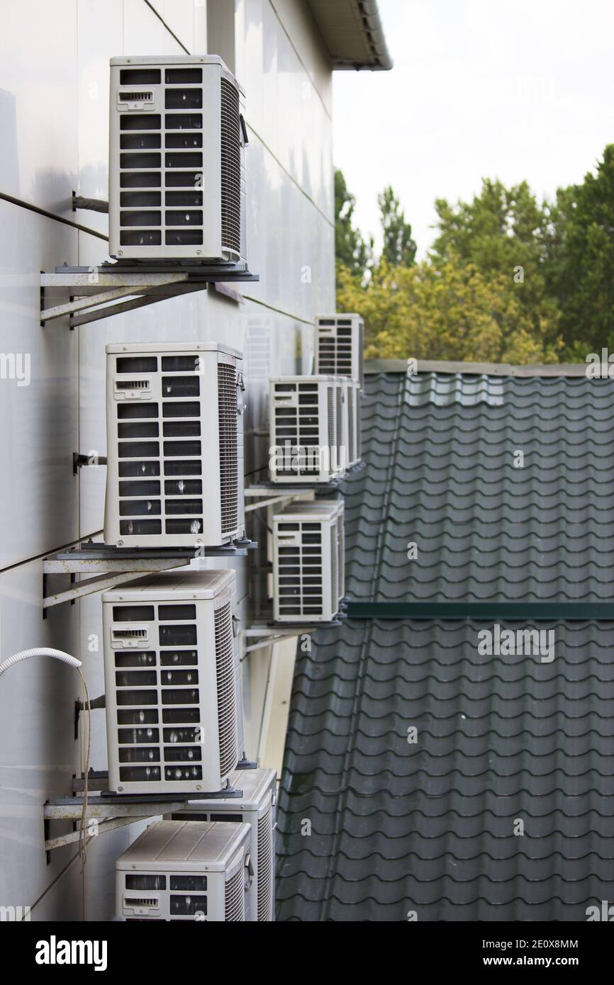 group of old outdoor air conditioner units on the facade of the house ...