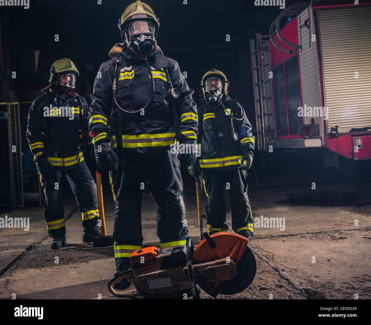 Group of three young fireman posing inside the fire department with ...