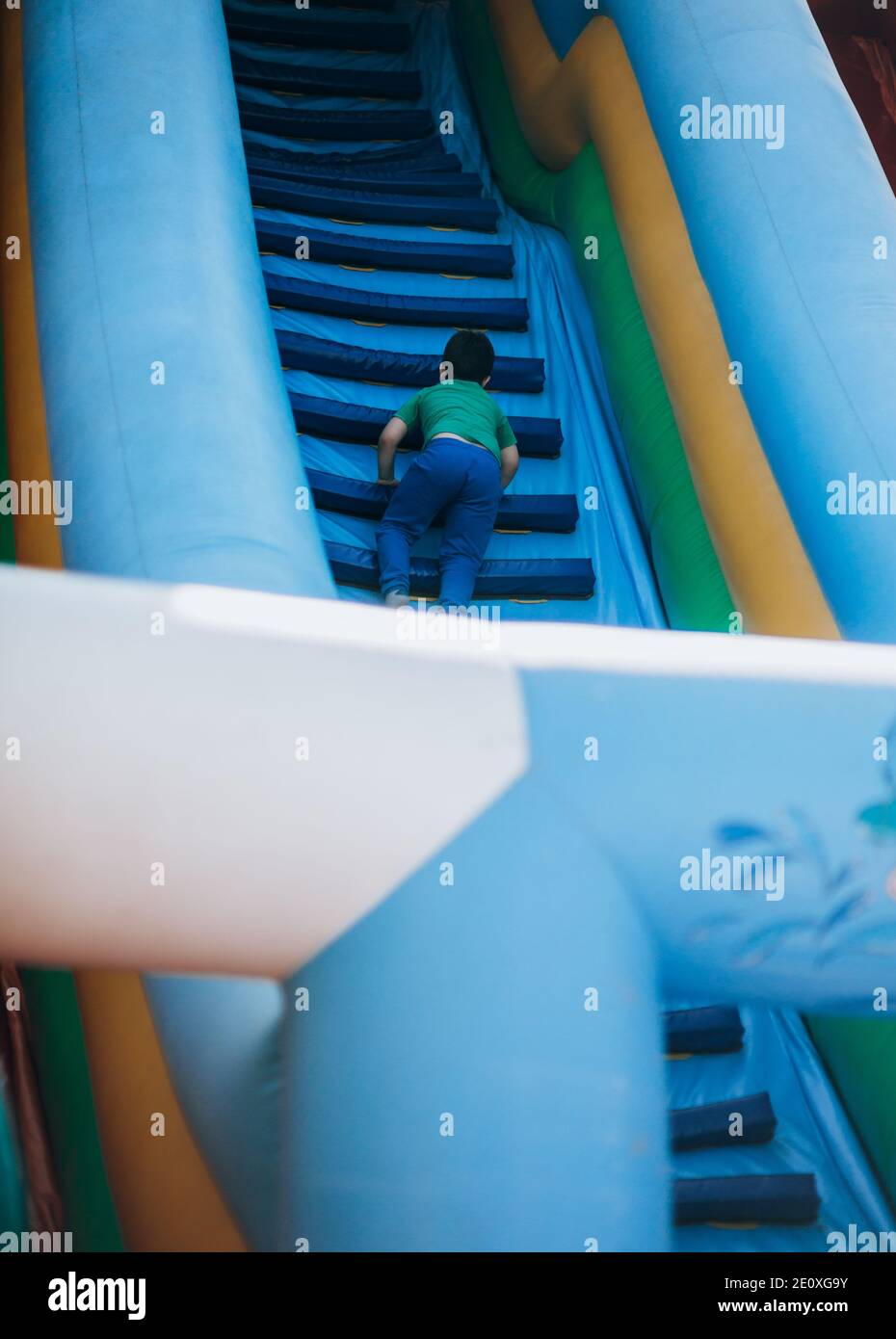 Cute joyful smiling boy going for a slide on the big inflatable slide ...