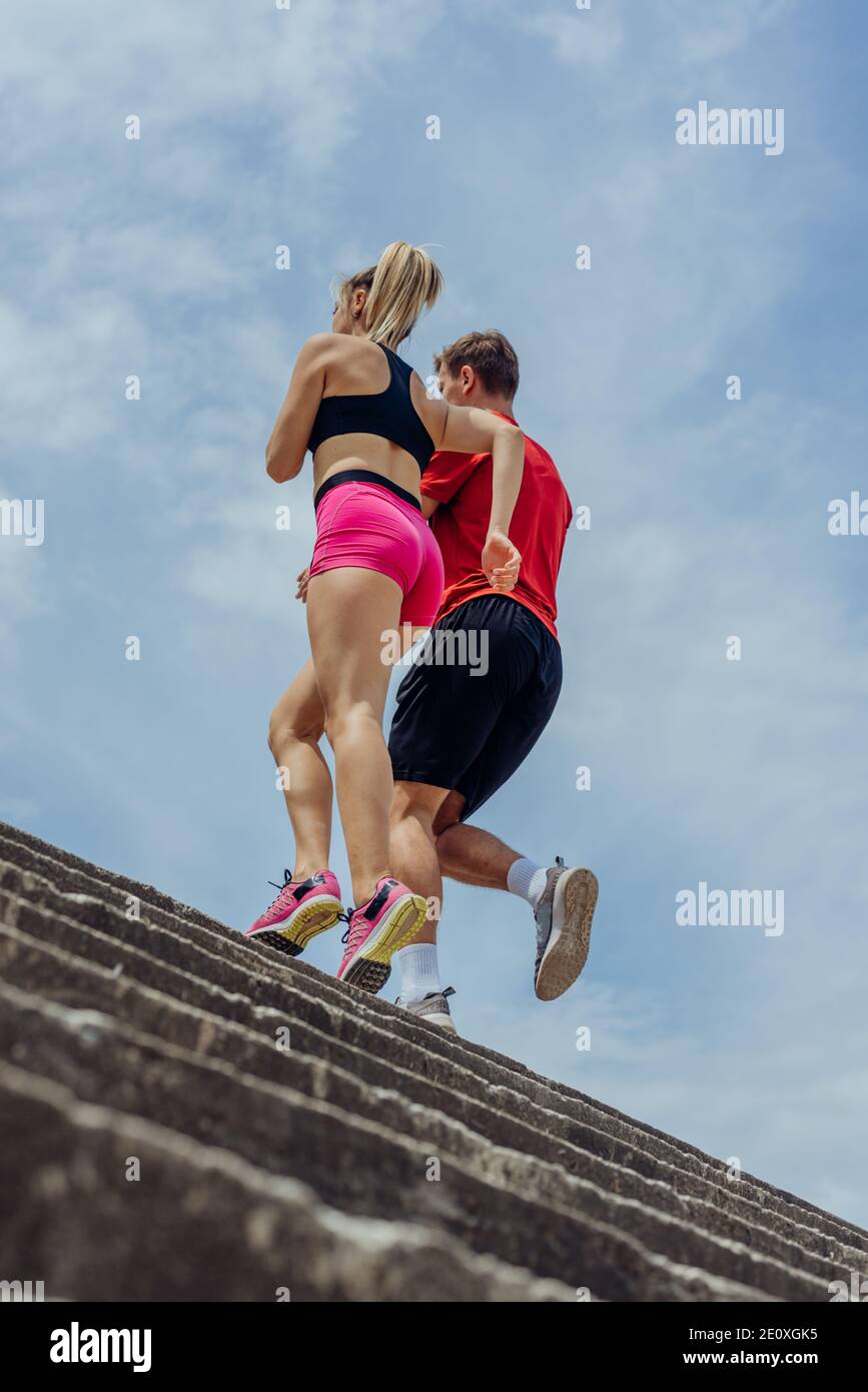 Low below angle view photo of a young caucasian couple running up ...