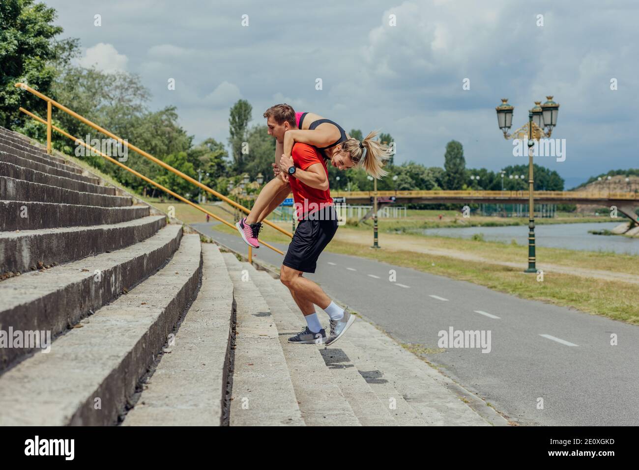 Male athlete carrying his female workout partner on his shoulders while ...